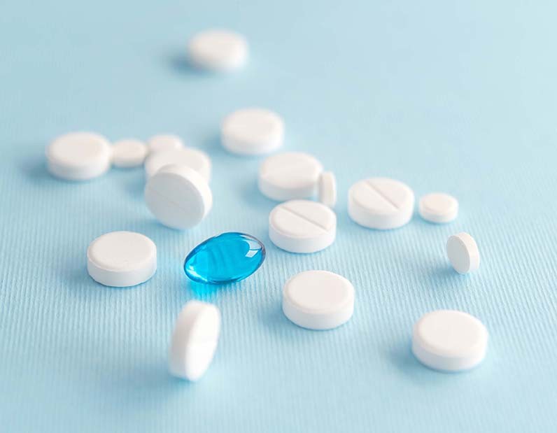 1close-up-white-tablets-with-one-blue-capsule